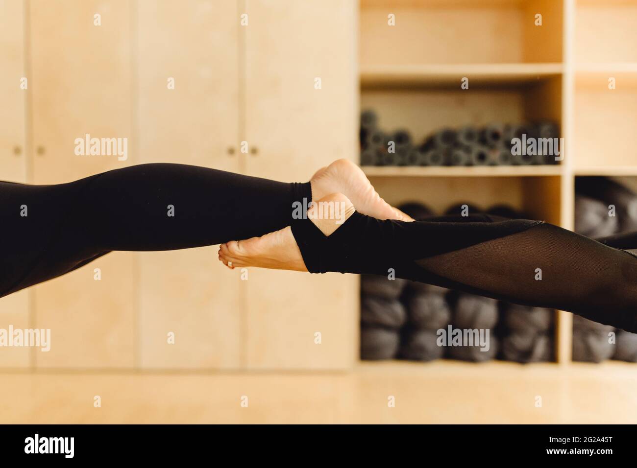 Raised legs of women in sportive swifting wear in moment of yoga asana ...