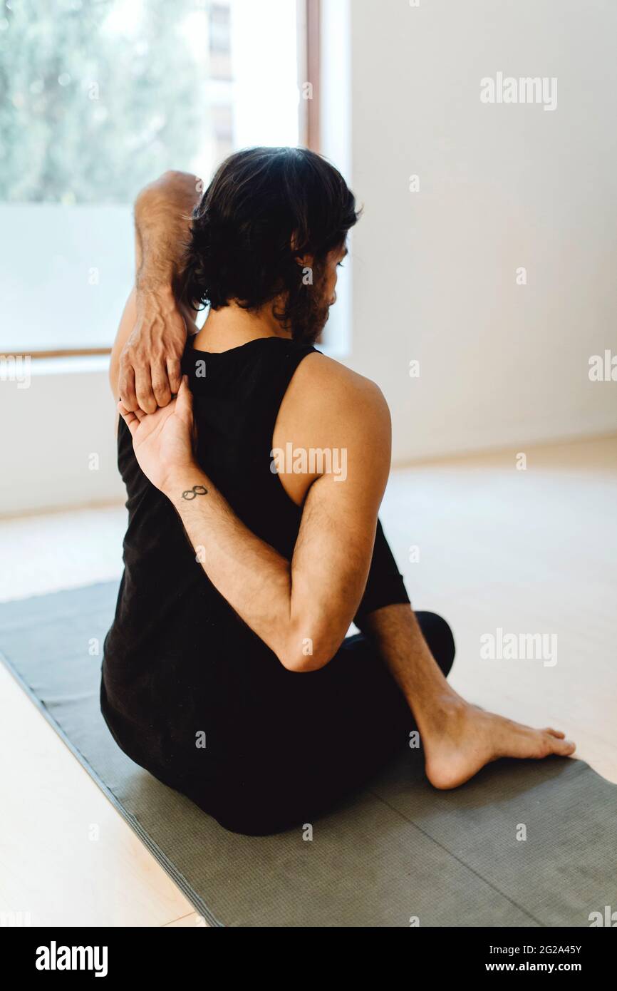 Side view of young slender man in sportive wear practicing yoga asana ...
