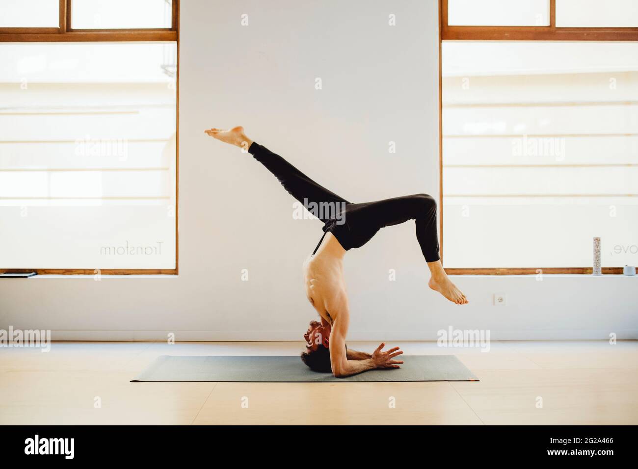 Side view of young slender man in sportive wear practicing yoga asana ...