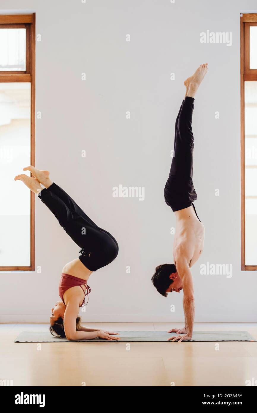 couple making a balance position in a yoga session in training room ...