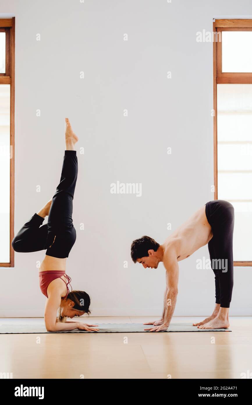 couple making a balance position in a yoga session in training room ...