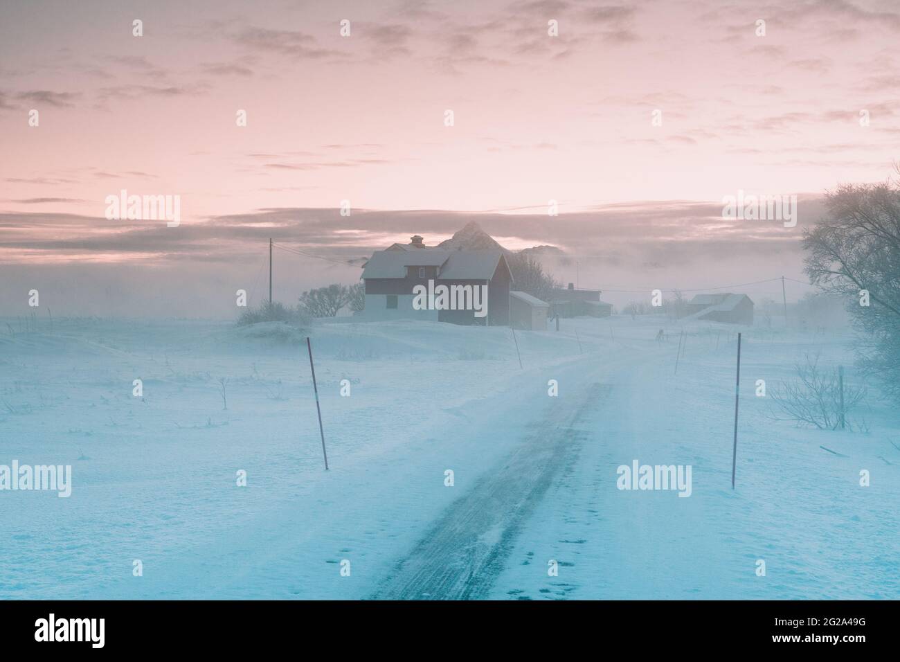Picturesque view of route running between wild lands in snow to houses ...