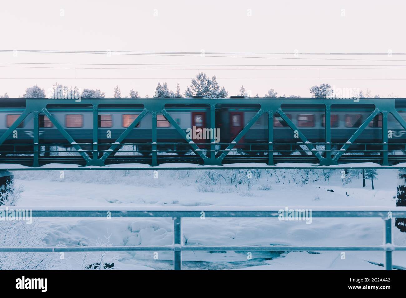 Side view of locomotive driving on bridge above water with ice in ...