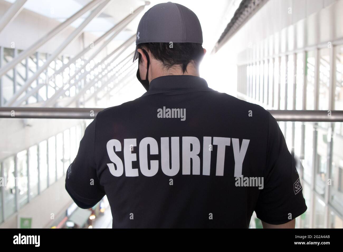 Rear view of a security guard in uniform patrolling in a commercial ...
