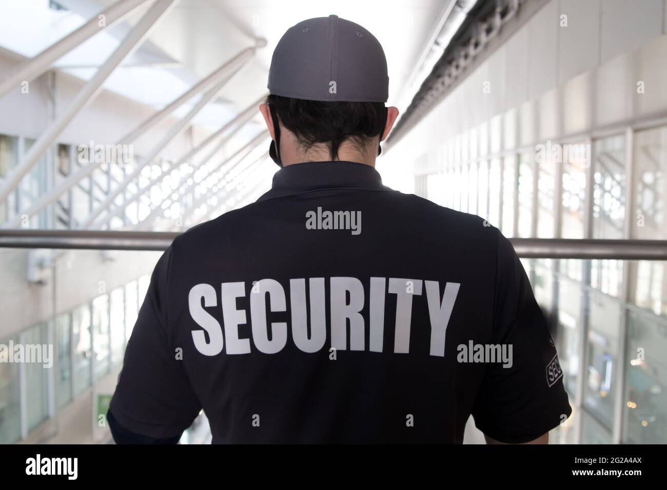 Rear view of a security guard in uniform patrolling in a commercial ...