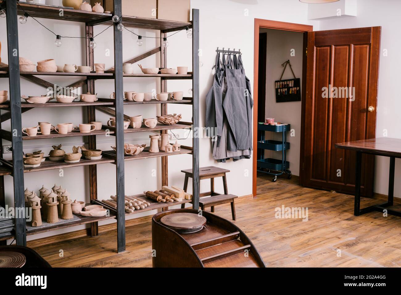 Clay products on shelves wooden machines for work gray aprons on wall ...
