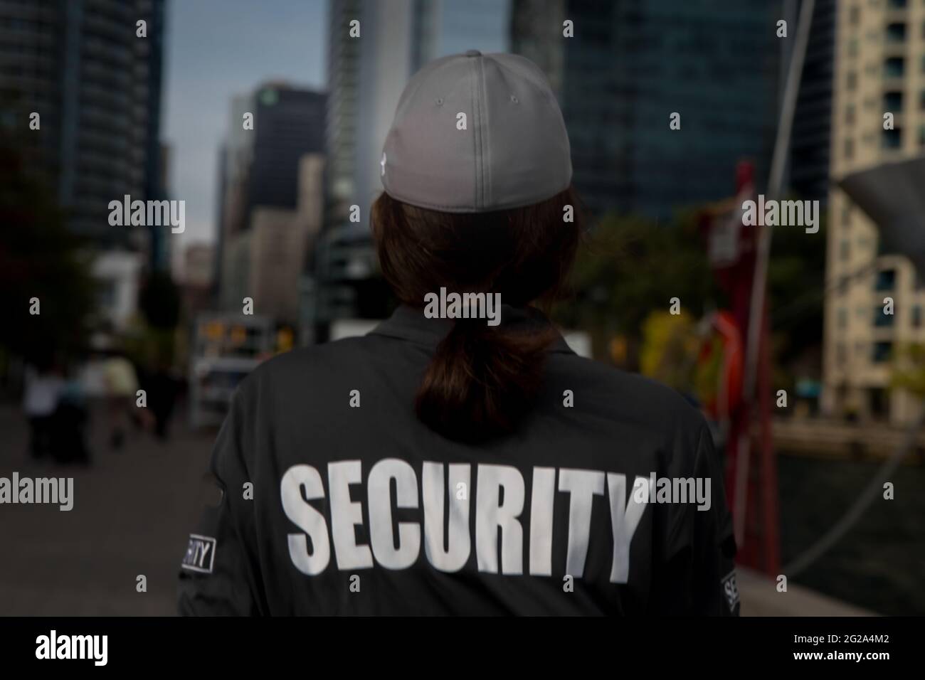 Back view of a female security guard in uniform patrolling a ...