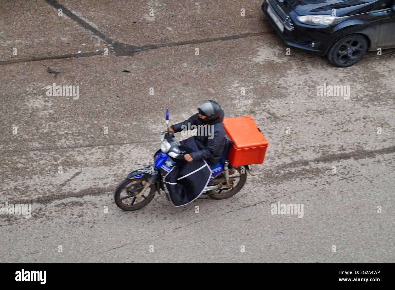 Delivery man riding a motorcycle on the road Stock Photo - Alamy