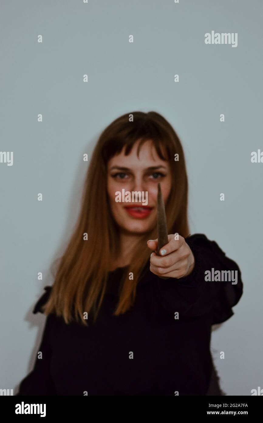 Vertical shot of a young artistic female pointing to a camera with a ...