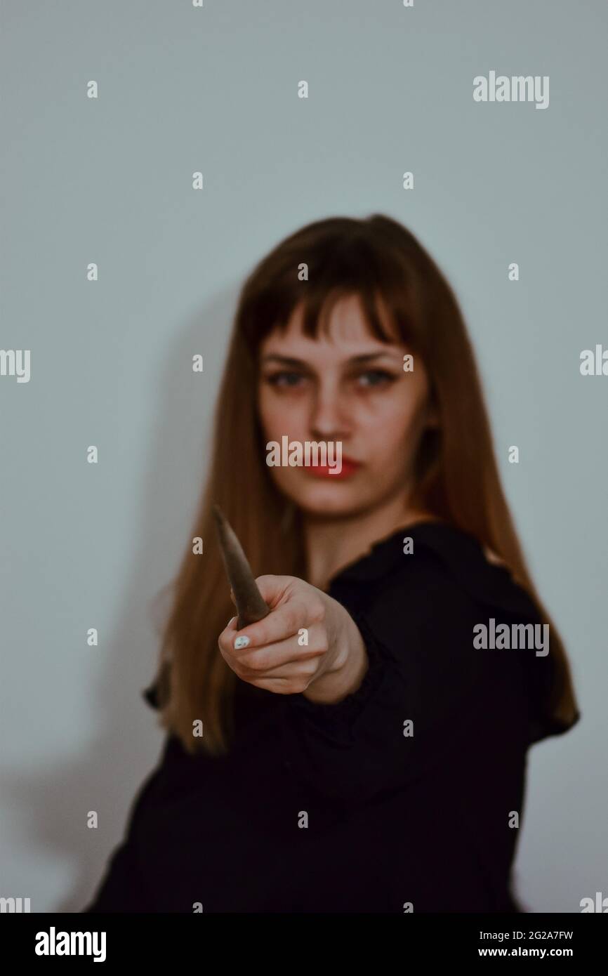 Vertical shot of a young artistic female pointing to a camera with a ...
