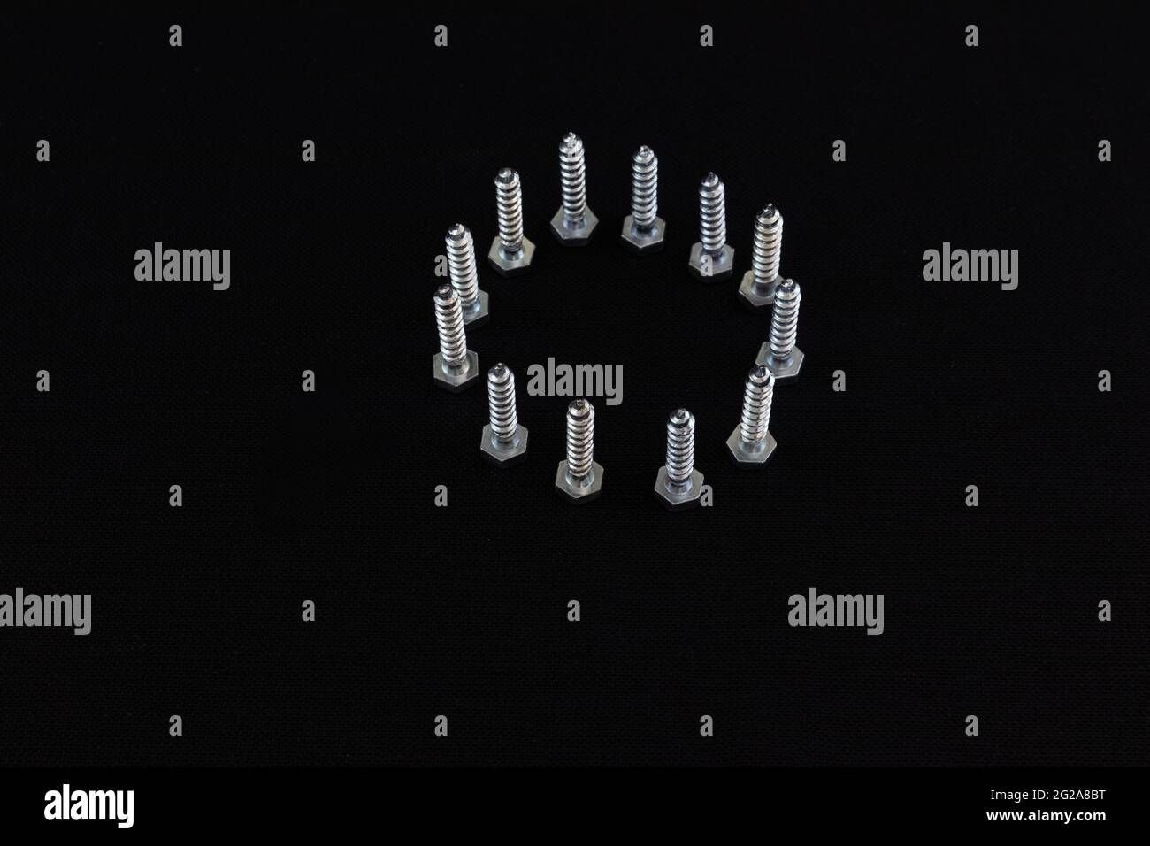 Closeup shot of a circle made of screws isolated on a black background ...