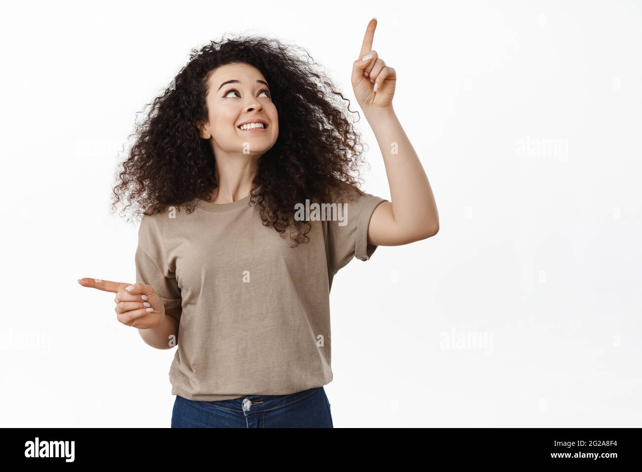 Happy young woman choosing between two products, pointing sideways and ...