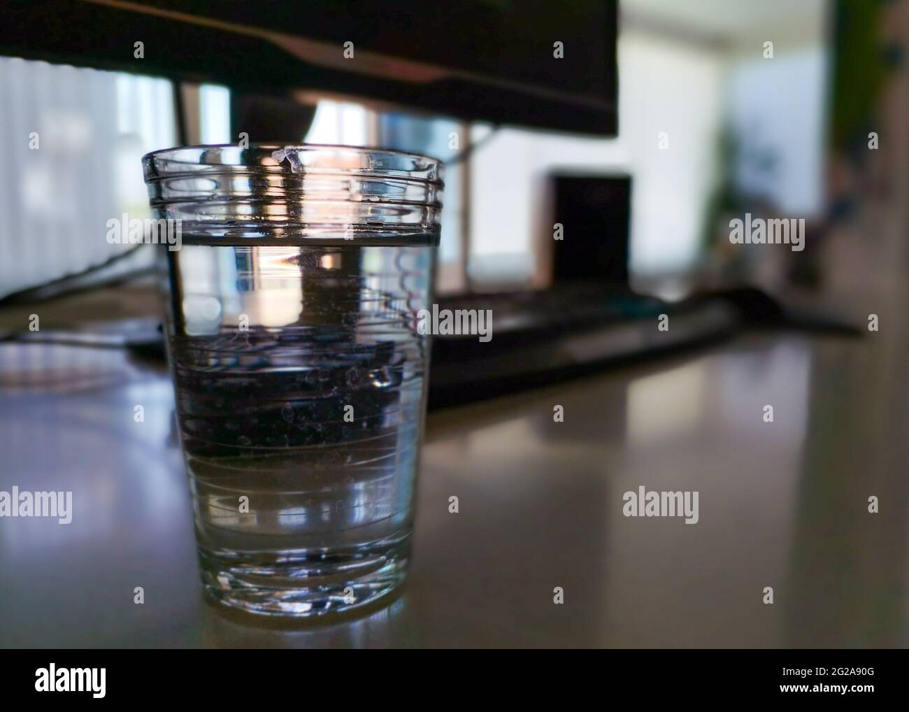 Transparent cup of water in front of computer Stock Photo - Alamy
