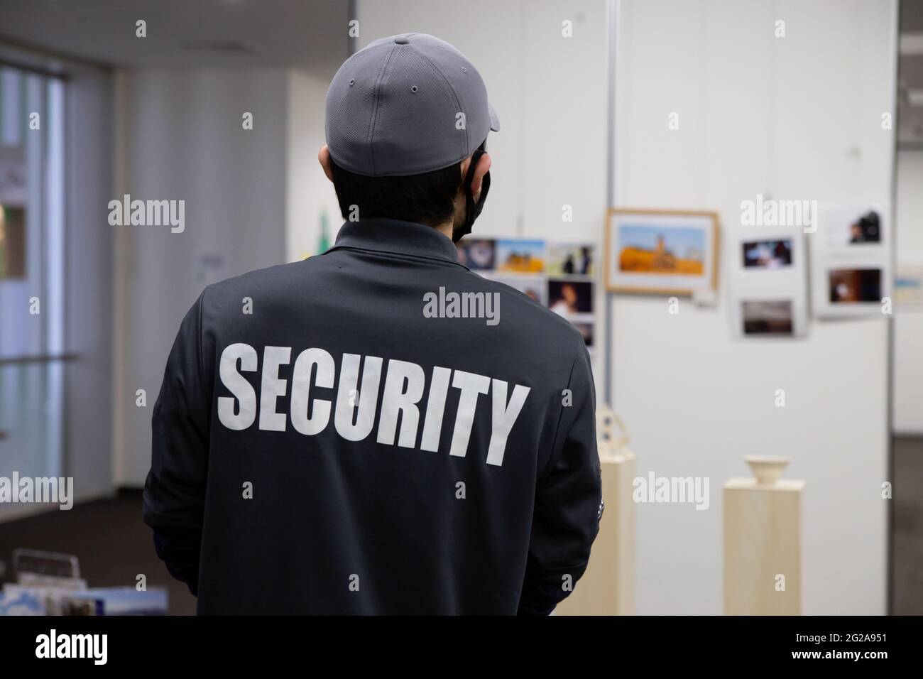 Rear view of a security guard in uniform patrolling in a commercial ...