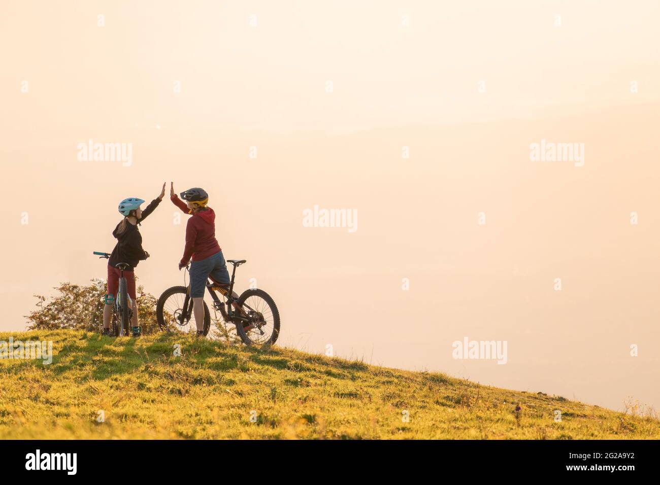Two happy woman high five over the sunset after a successful mountain ...