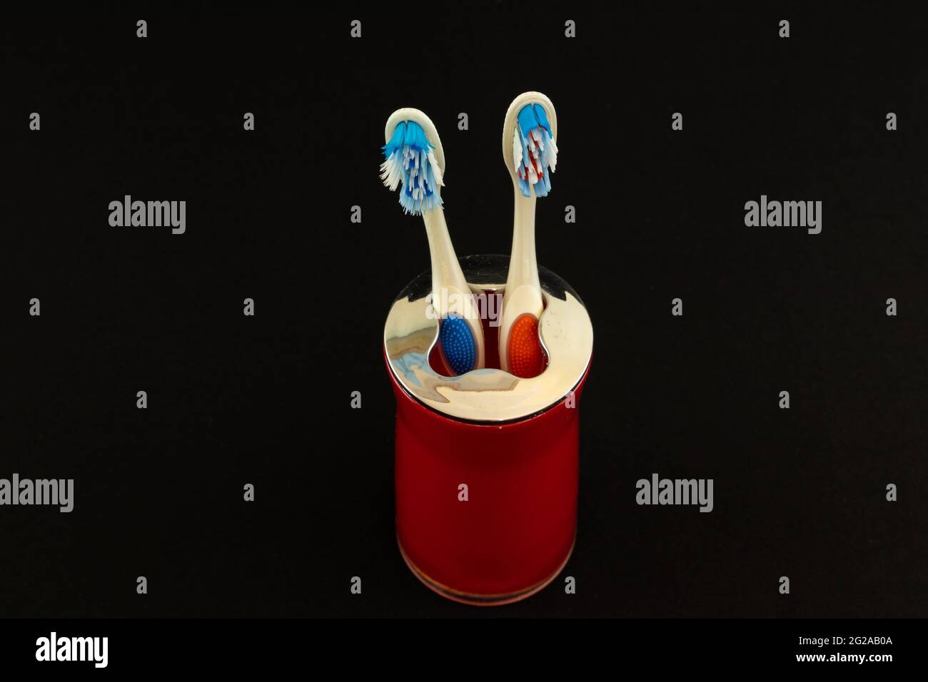 Toothbrushes in a cup isolated on a black background Stock Photo - Alamy