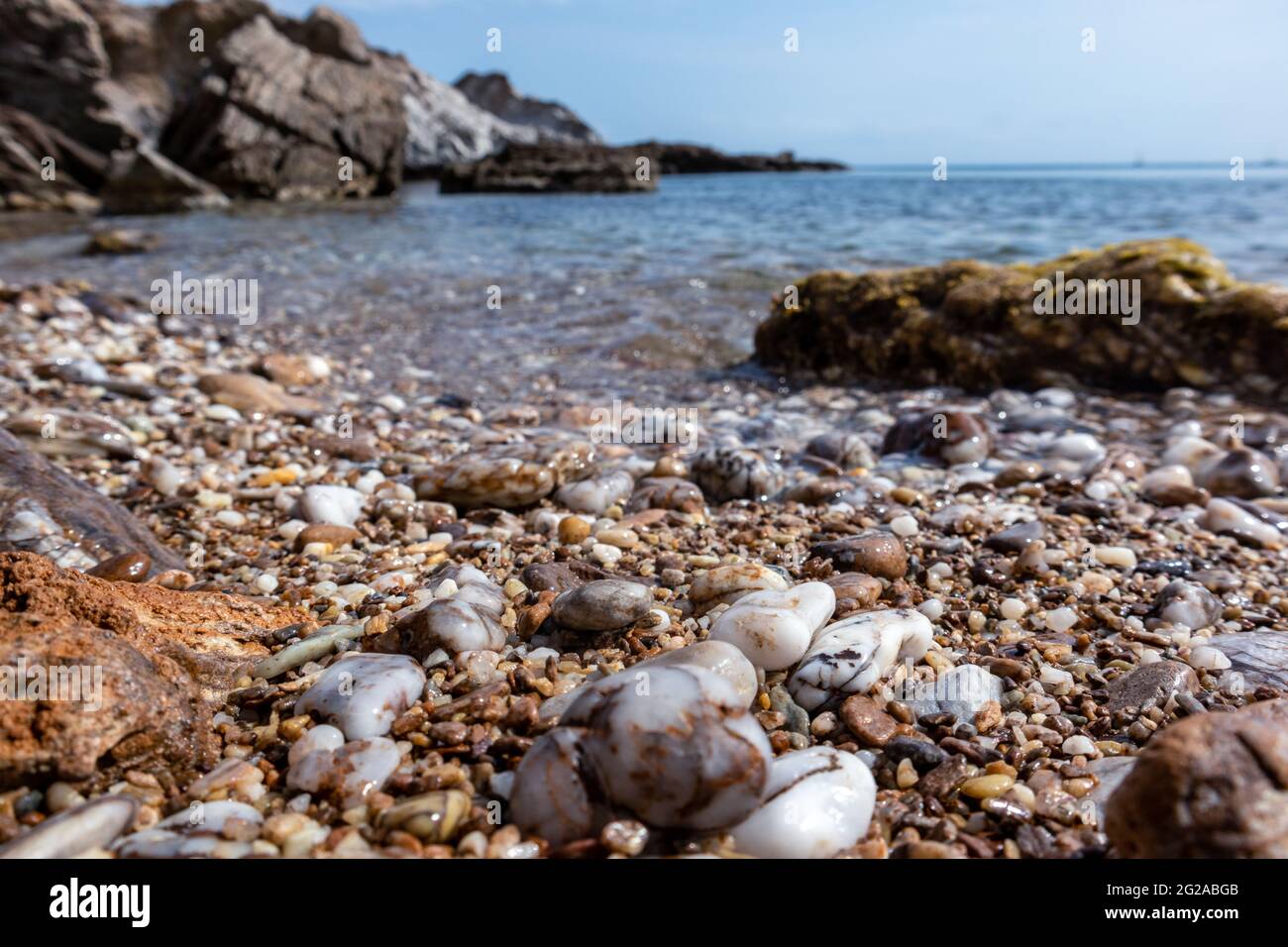 Marble stones close-up on wild mediterranean sea pebble beach with ...