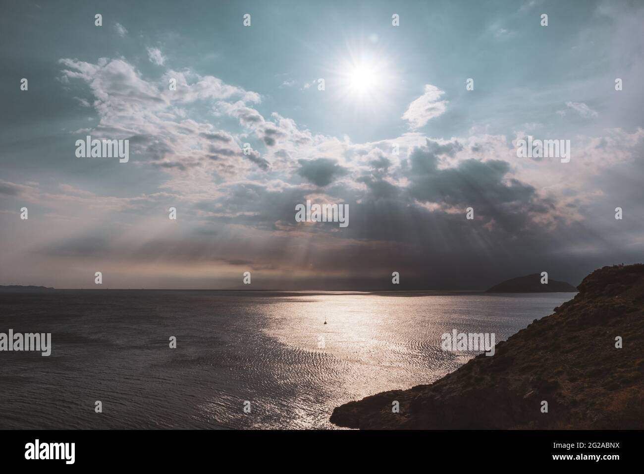 Sun rays shining though clouds over the sea in Greece. Cape Sounion ...