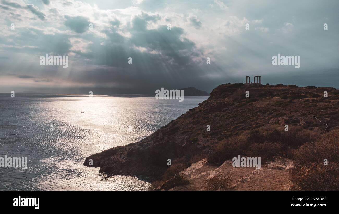 Sun rays shining though clouds over the Temple of Poseidon at Cape ...