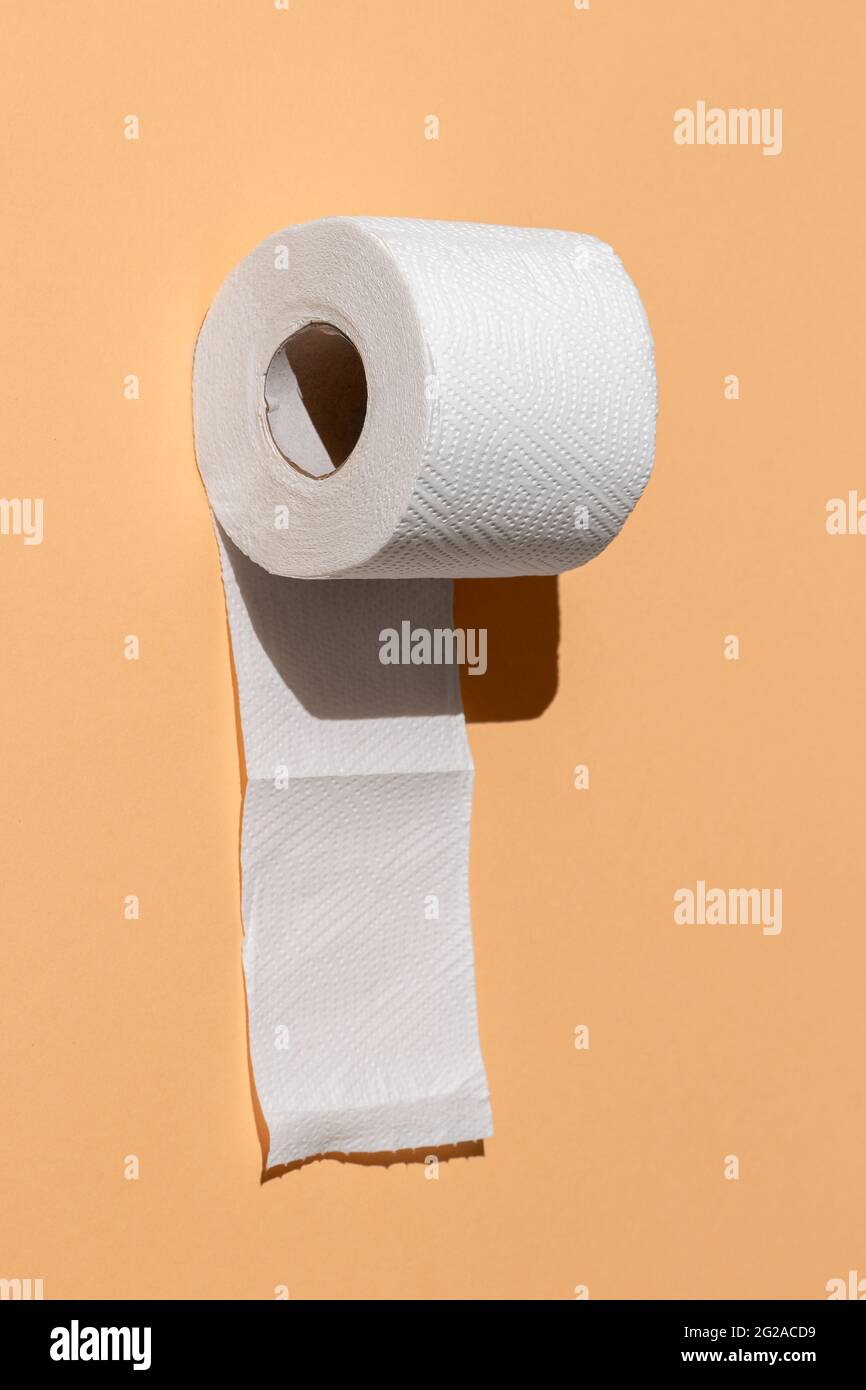 roll of a perforated toilet paper isolated on a sand color background ...