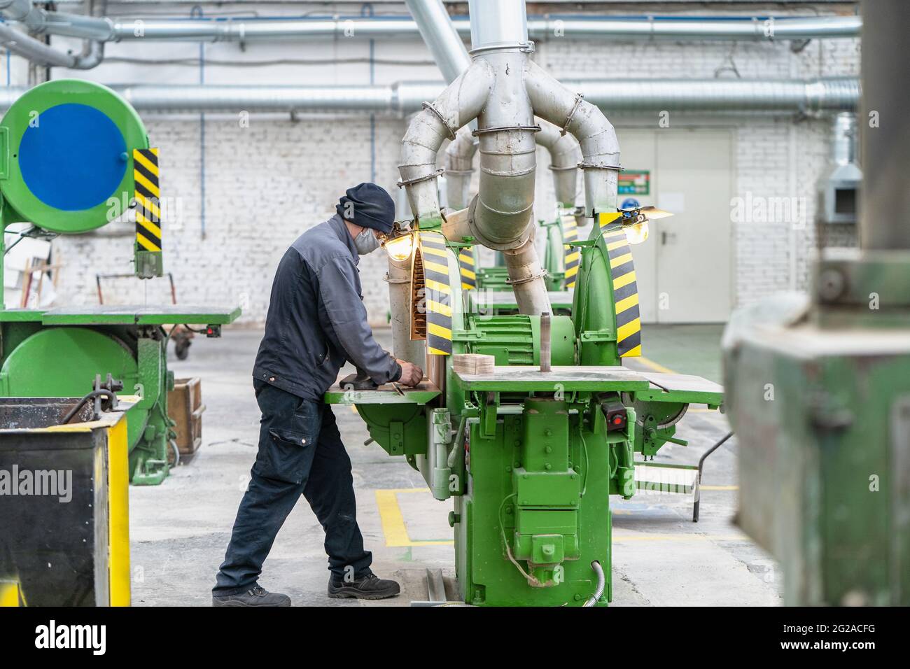 Unrecognizable worker mask in timber workshop works with big grinder ...