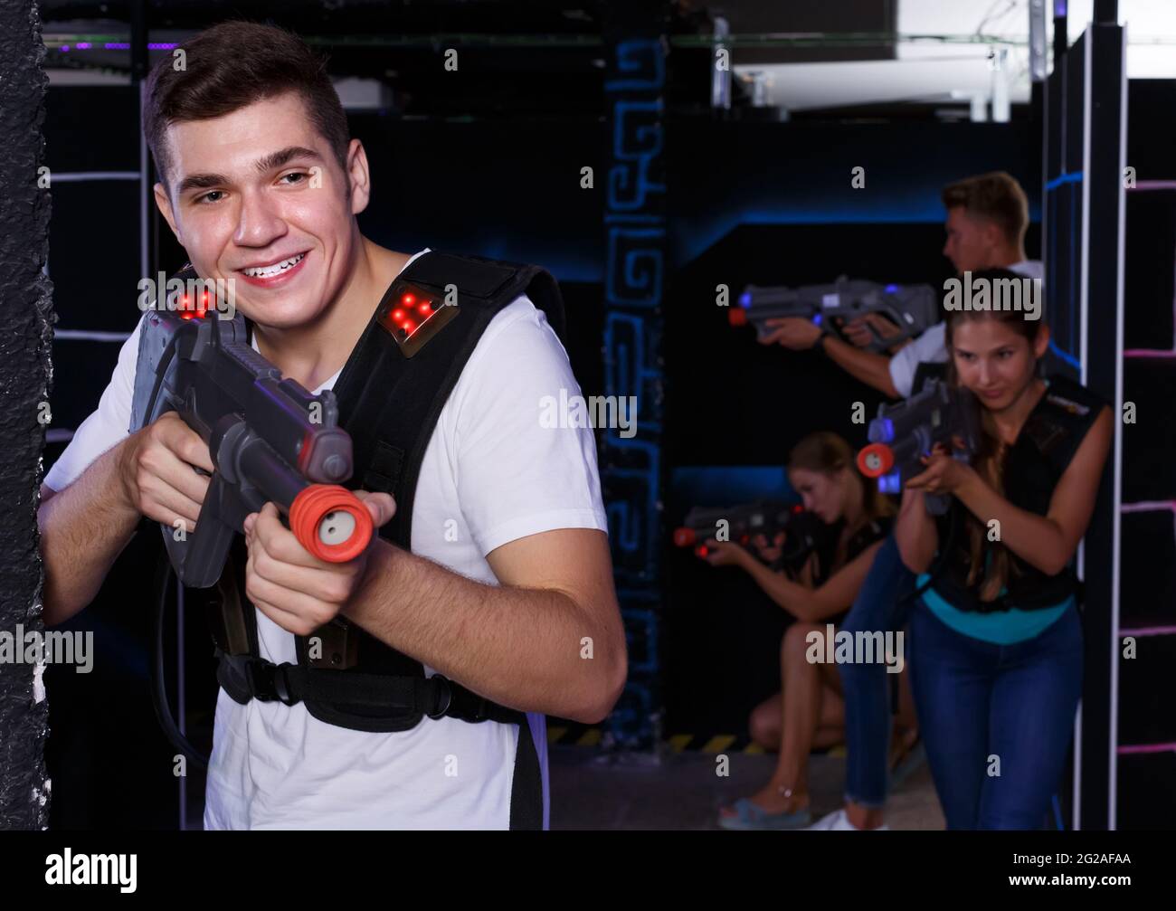 Excited guy holding laser pistol, playing laser tag with friends in ...