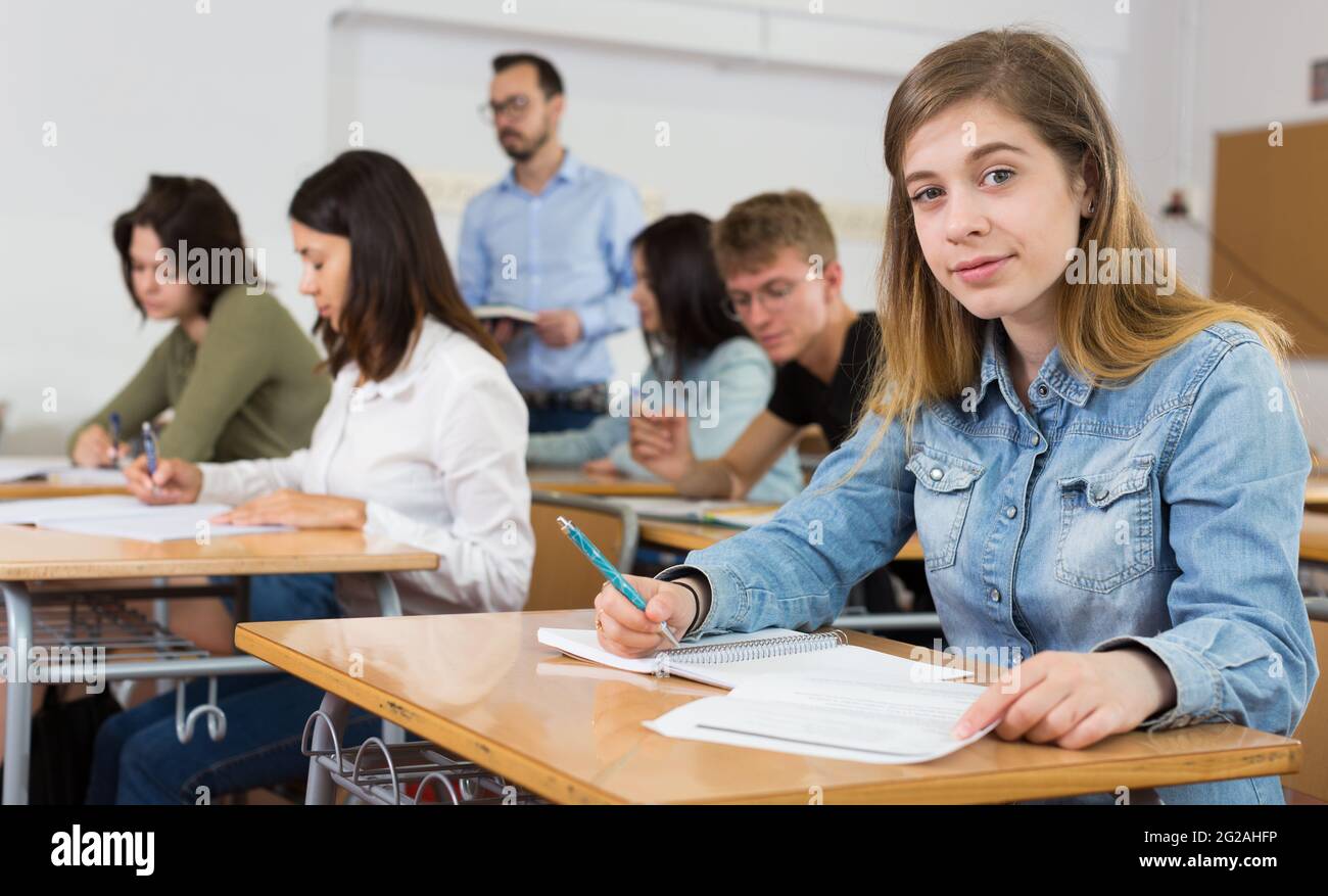 Young girl is writing test and thinking about questions at the desk ...