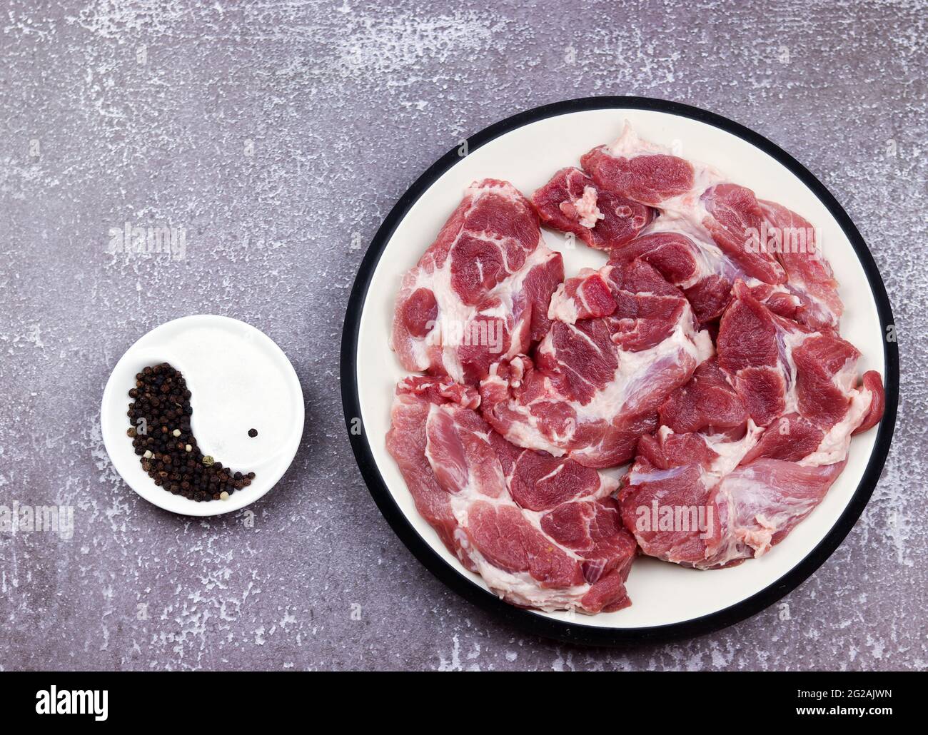 Raw blade steak from pork shoulder in a white plate on a dark wooden ...