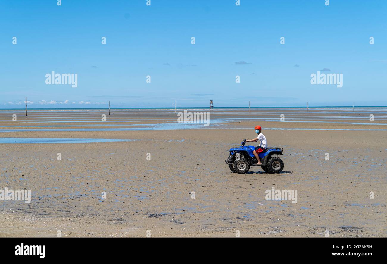Beach with low tide and a Quad motorbike riding along the beach Stock ...