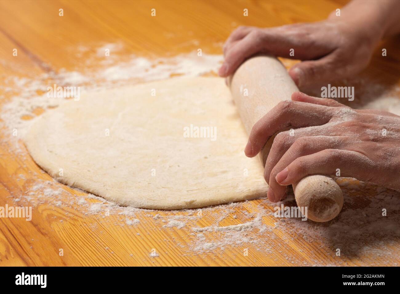 Hands with rolling-pin make dough for pizza. Italian pizza cooking ...