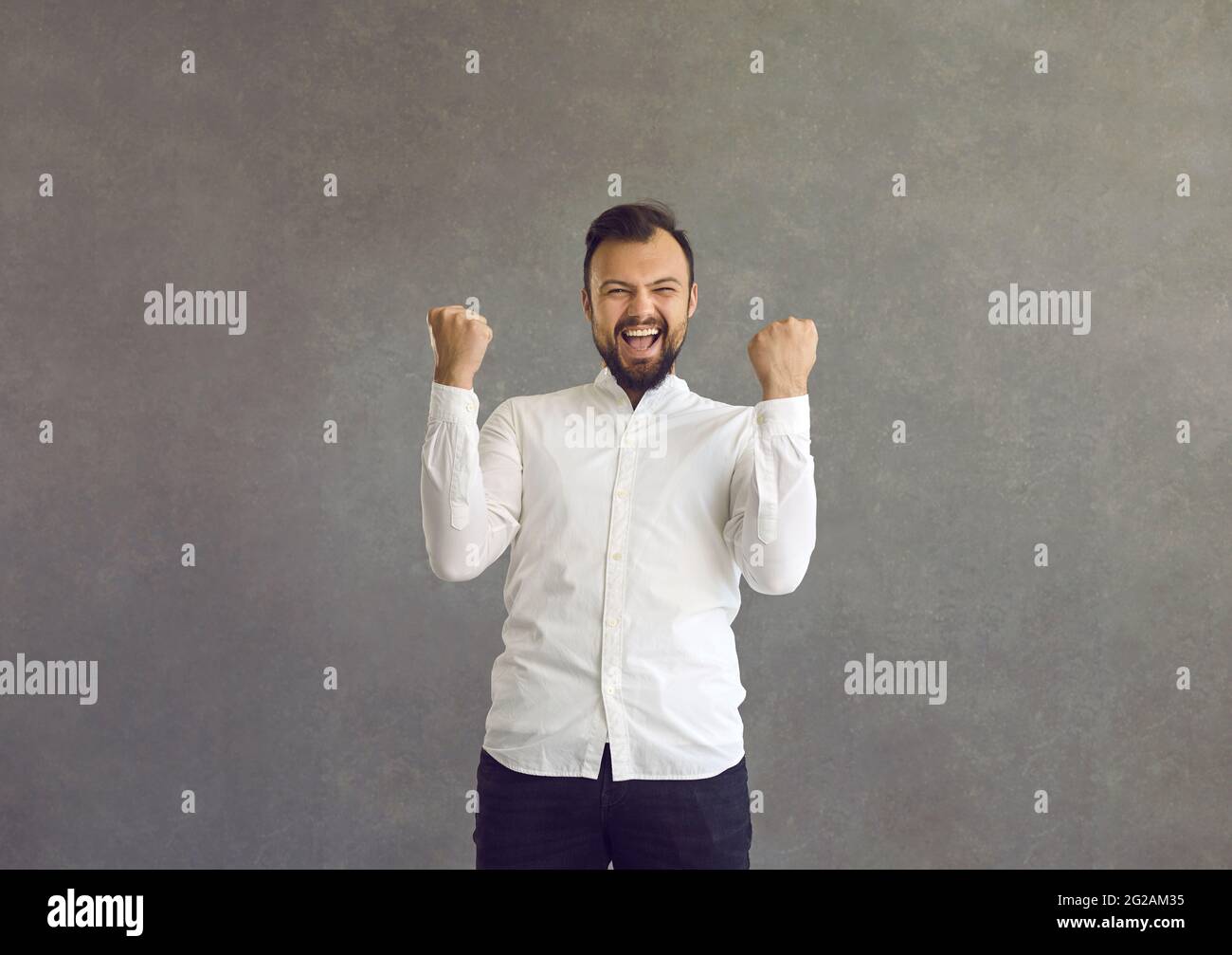 Half-length portrait of happy cheering man with clenched fist stand on ...