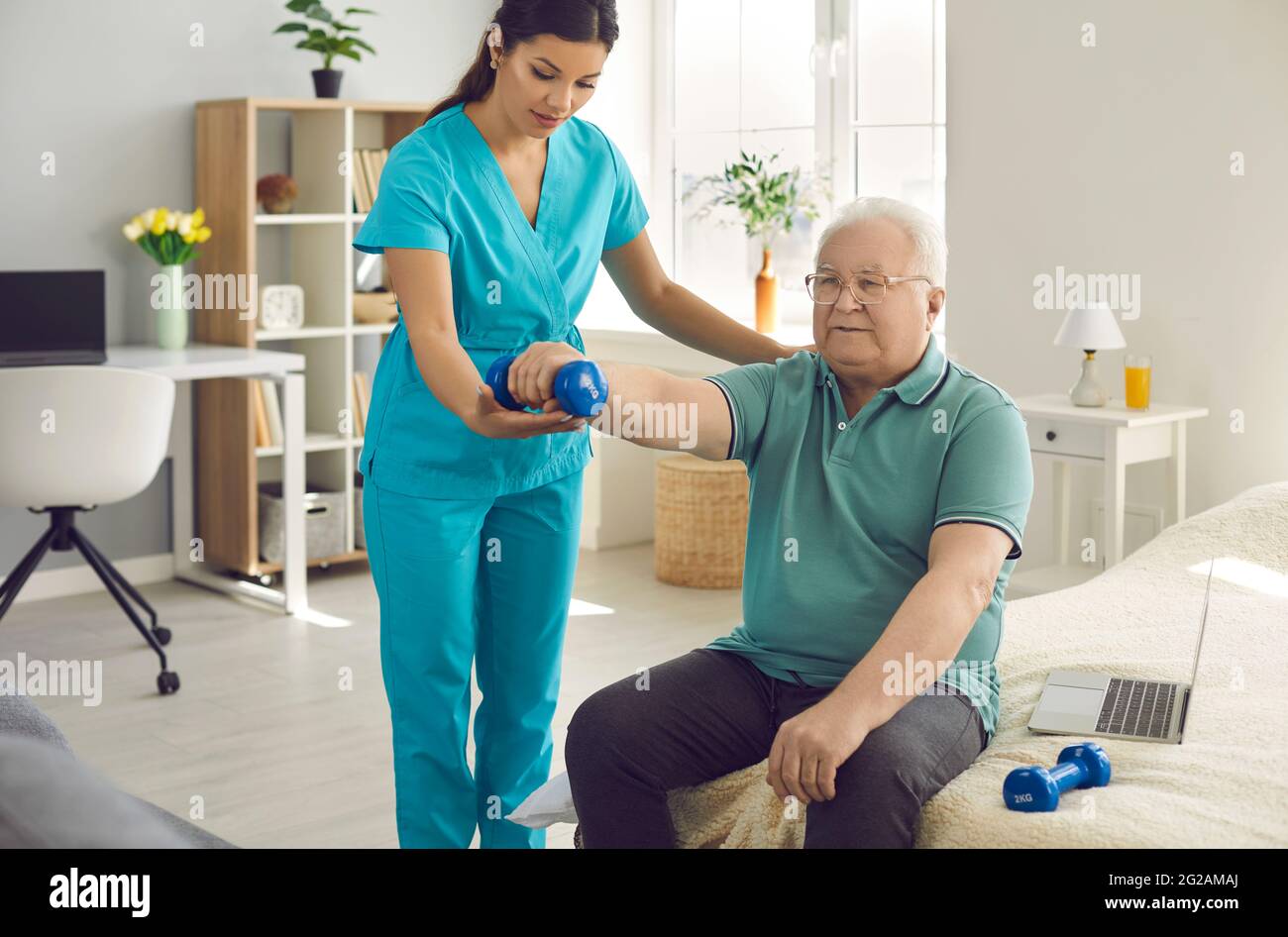 Physical therapist nurse helping patient to exercise with dumbbells at ...