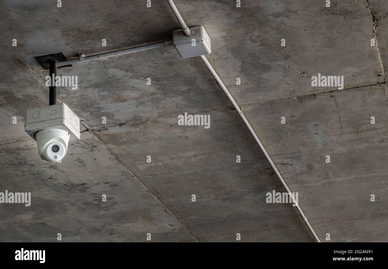 Modern surveillance cameras for ceiling mounted on concrete wall in the ...