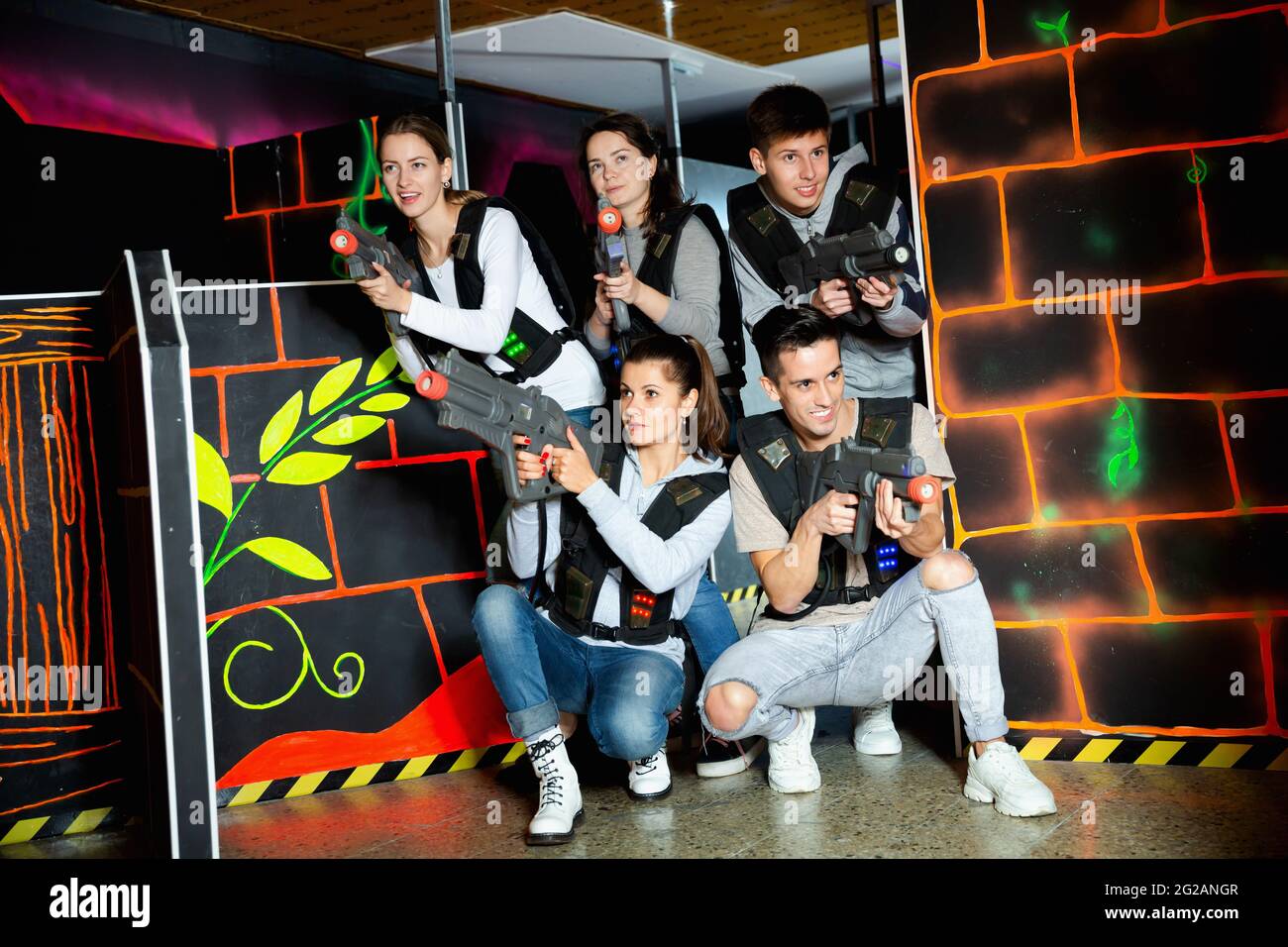 Happy young people with laser pistols posing together on dark laser tag ...