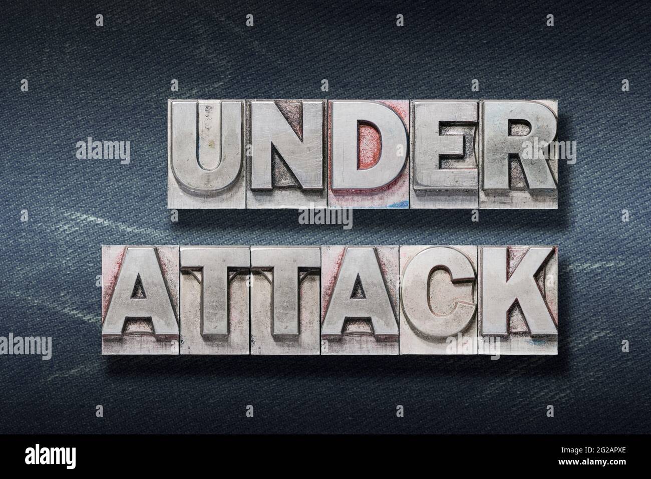 under attack phrase made from metallic letterpress on dark jeans ...