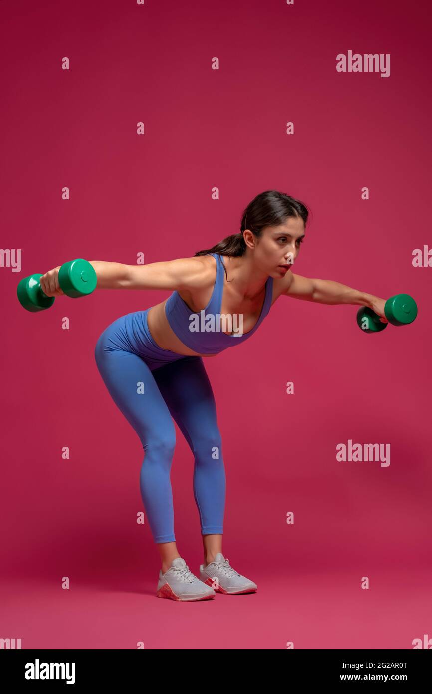 Athletic girl doing shoulders exercise on maroon background Stock Photo ...