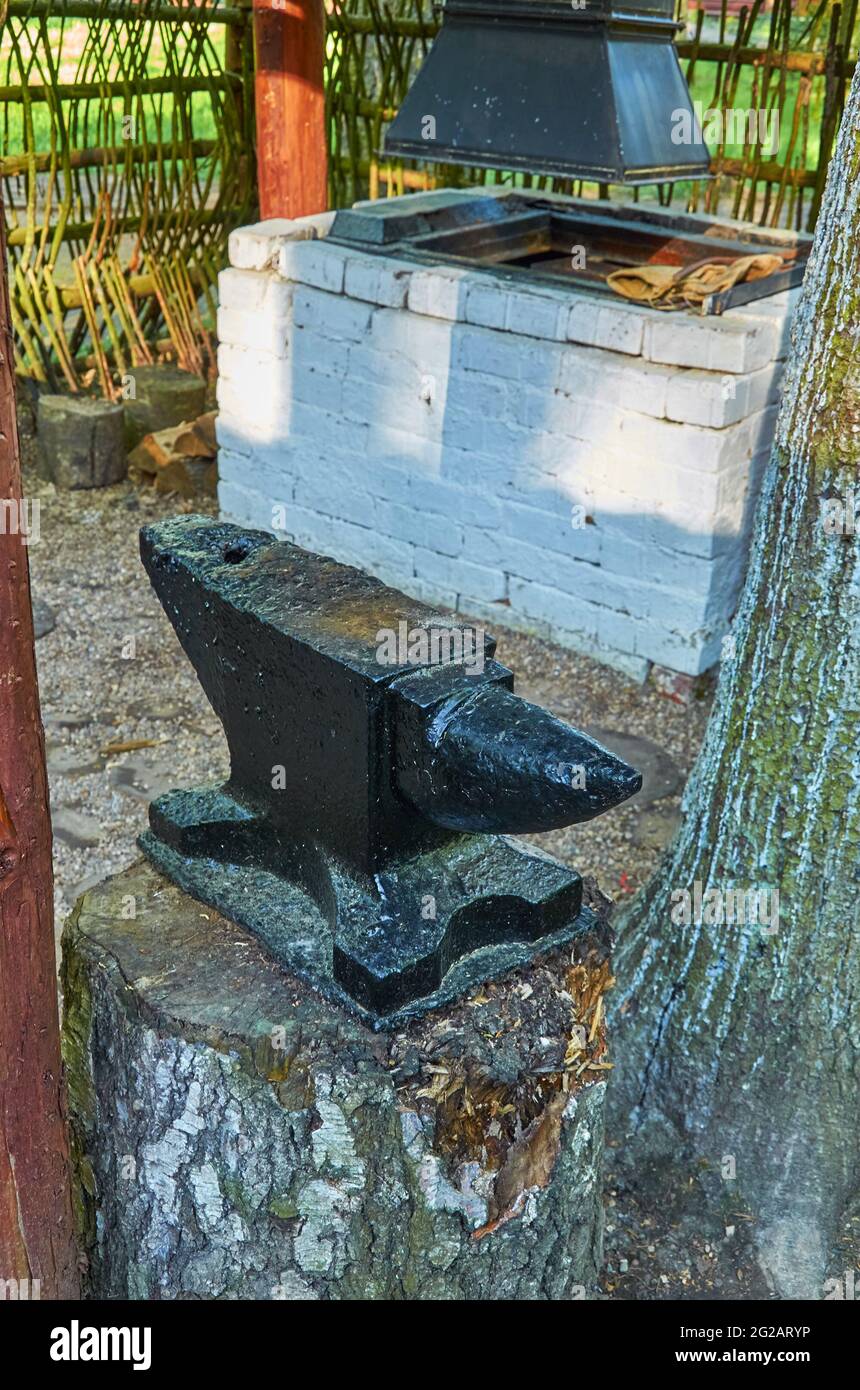 An old anvil painted black stands on a stump. Close-up. Vertical format ...