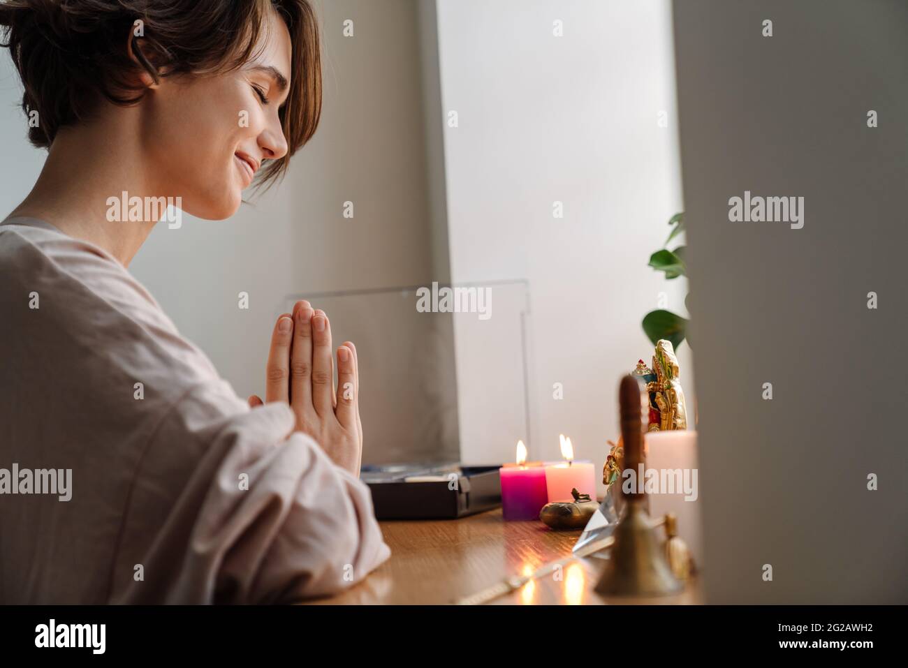 Happy beautiful girl smiling while praying at home shrine indoors Stock ...