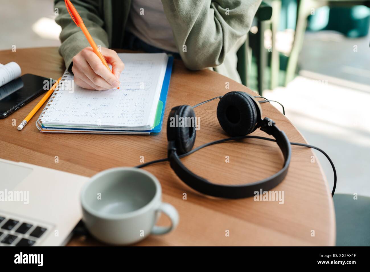 Caucasian girl writing down notes in exercise book while sitting in ...