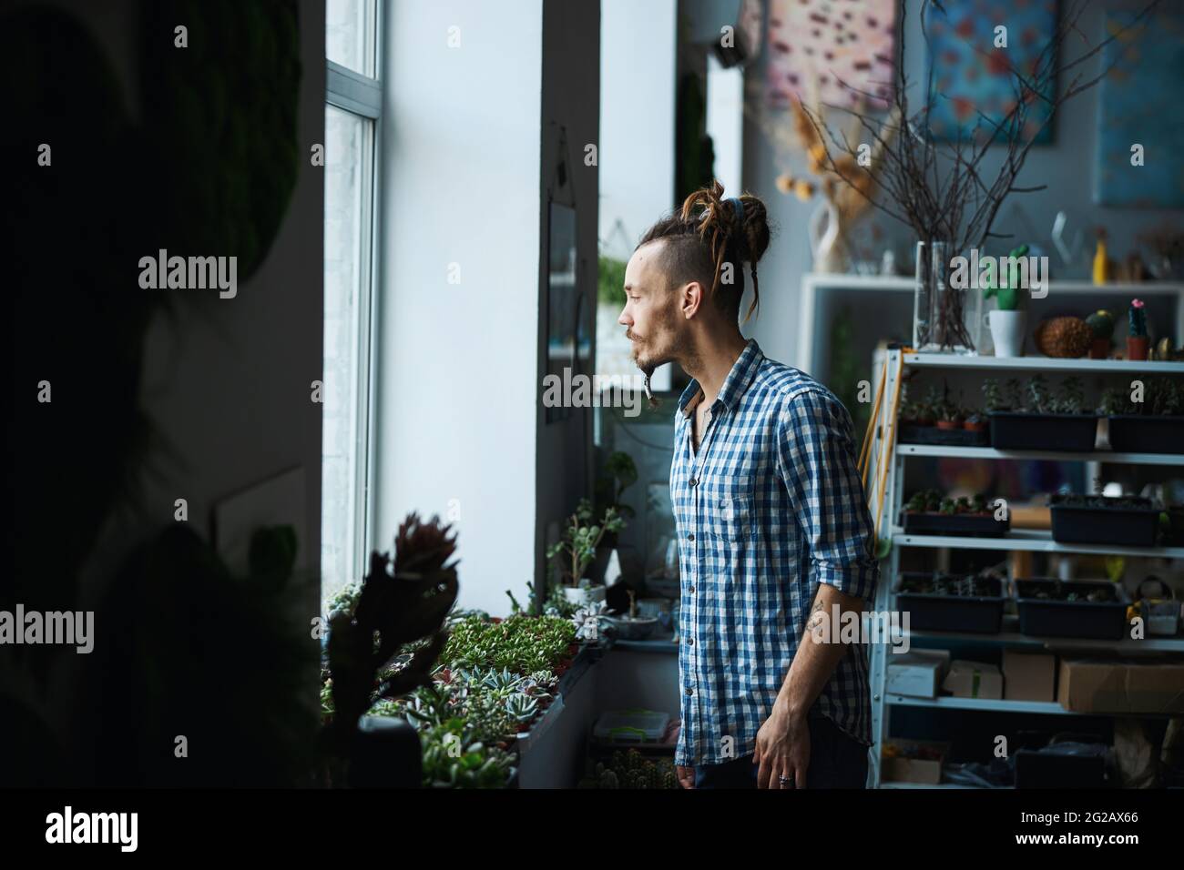 Handsome young man looking out the window at home Stock Photo - Alamy