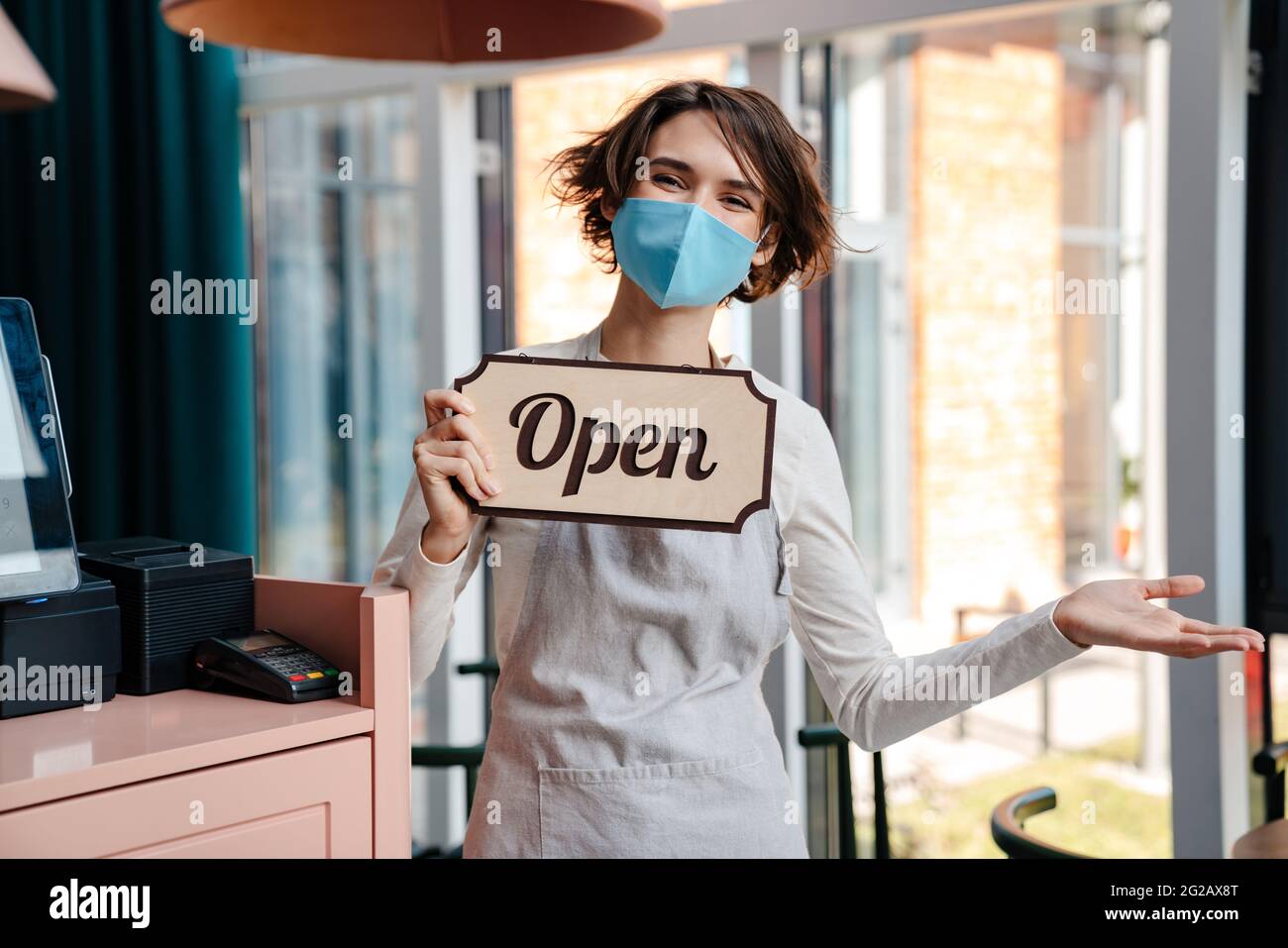 Happy waitress holding open sign while reopening cafe after COVID-19 ...