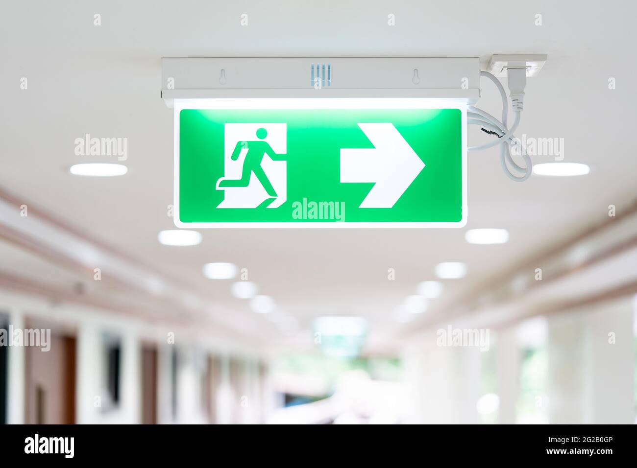 A Arrow light box sign of EMERGENCY FIRE EXIT is hung on the ceiling in ...