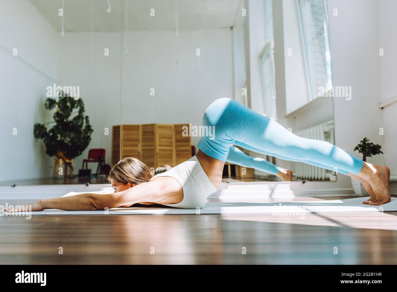Young female do complex of stretching yoga exercises on floor in light ...