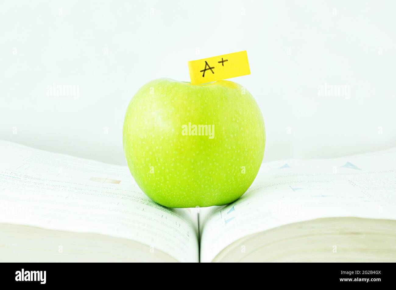 Green apple with A+ sign on textbook Stock Photo - Alamy