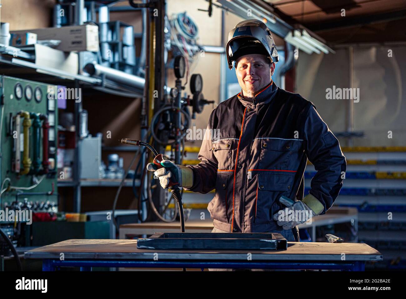 Portrait of a smiling welder posing at his workplace in the factory ...