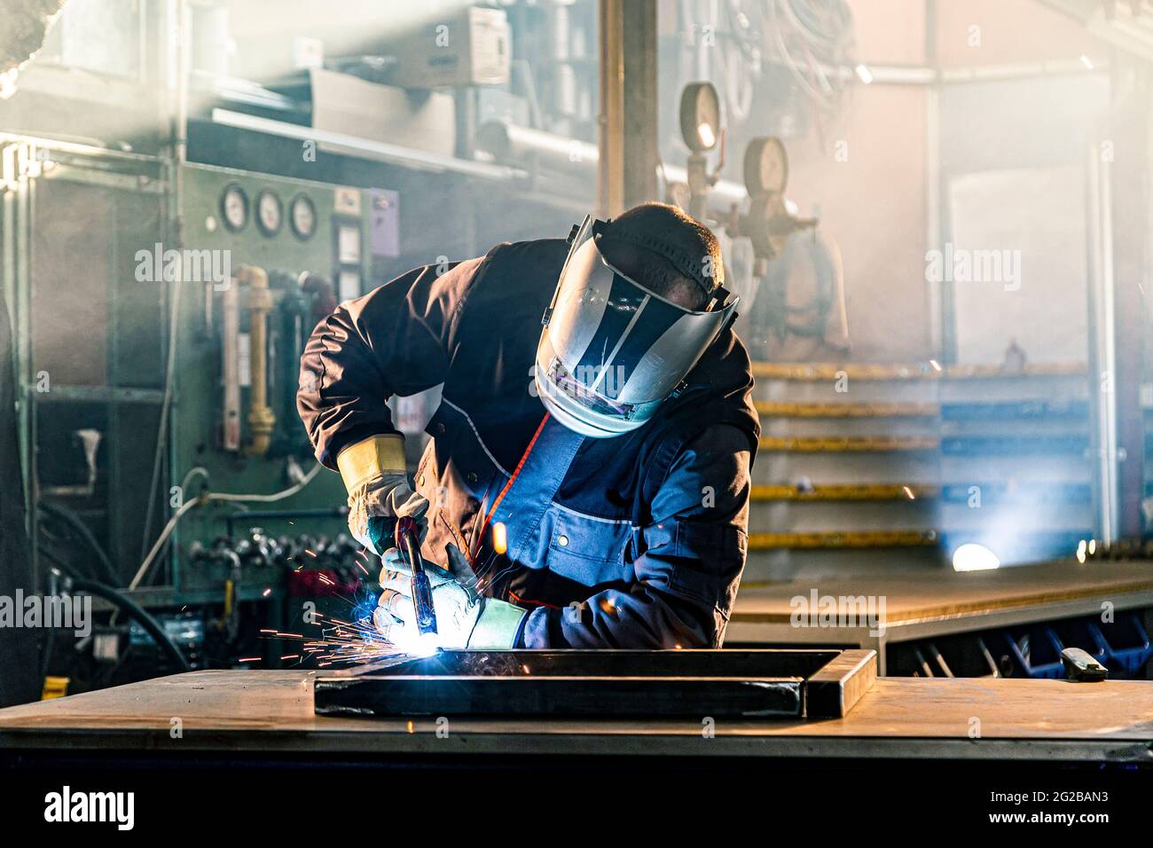 The welder performs welding task at his workplace in the factory, while ...