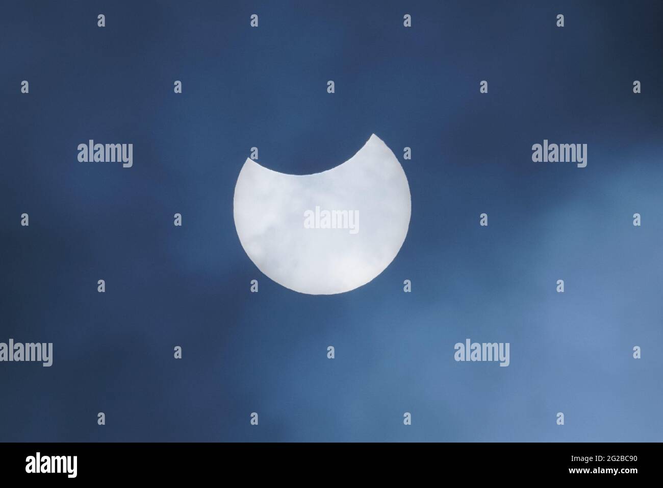 Partial solar eclipse seen through the clouds Stock Photo - Alamy