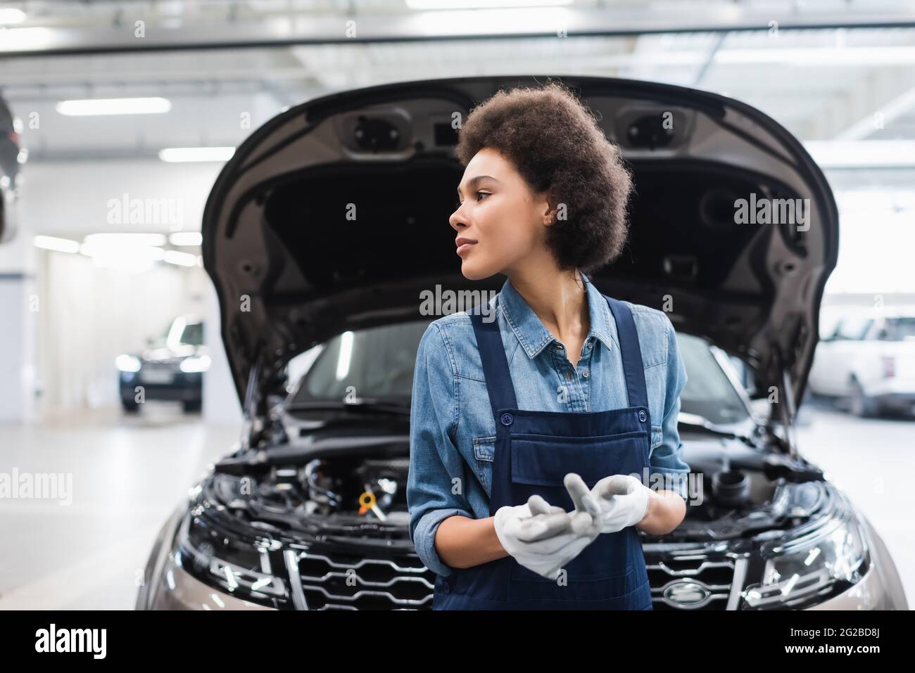 young african american mechanic standing near car with open hood and ...