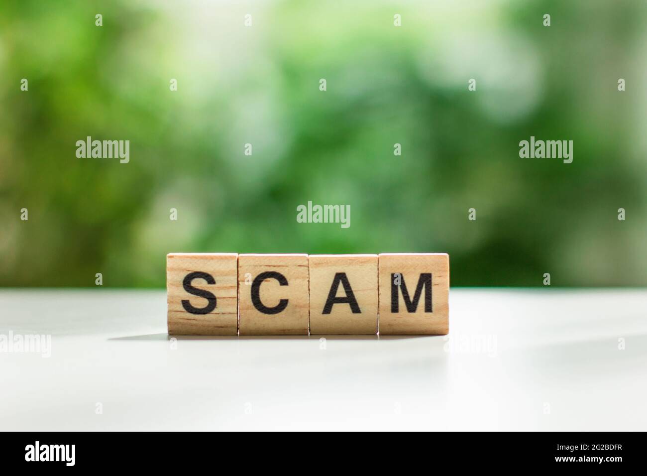 Word scam message sign of wooden cubes on a light table against a ...