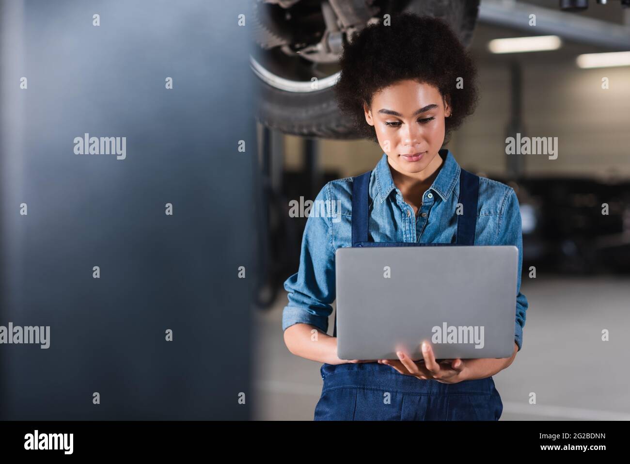 young african american mechanic typing on laptop in garage Stock Photo ...